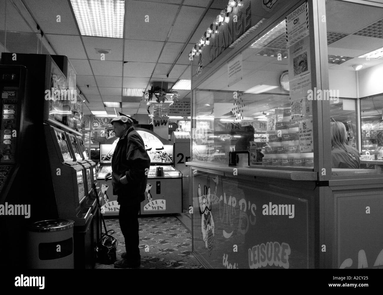 black and white image off an arcade with people playing the machines ...