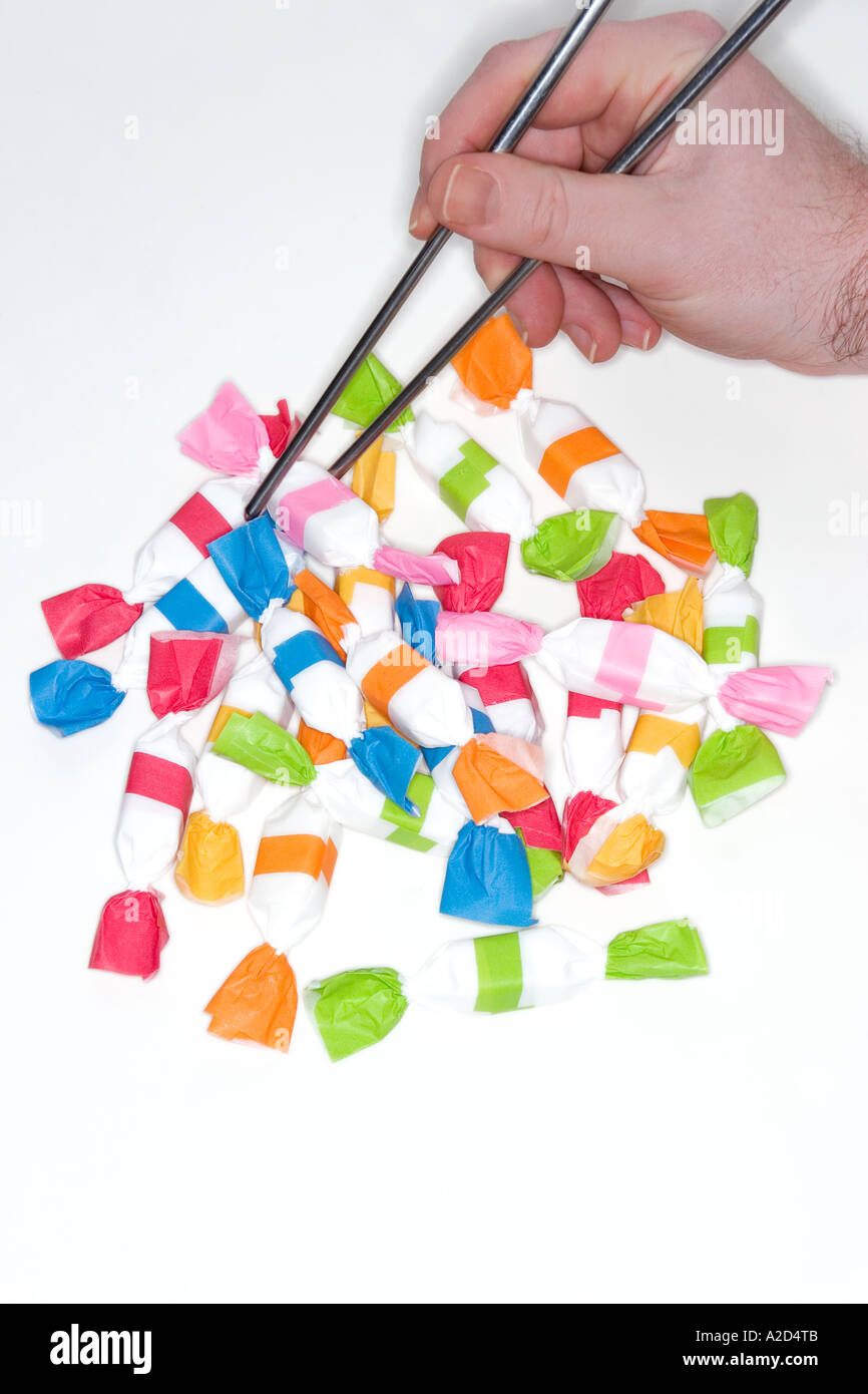 Silver chopsticks taking a piece of candy Stock Photo - Alamy