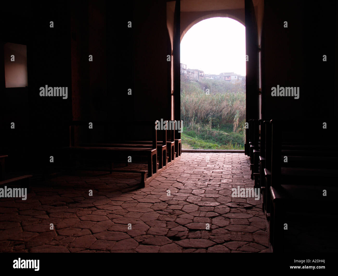 light falling on hexagonal tiled floor pews and doorway of ...