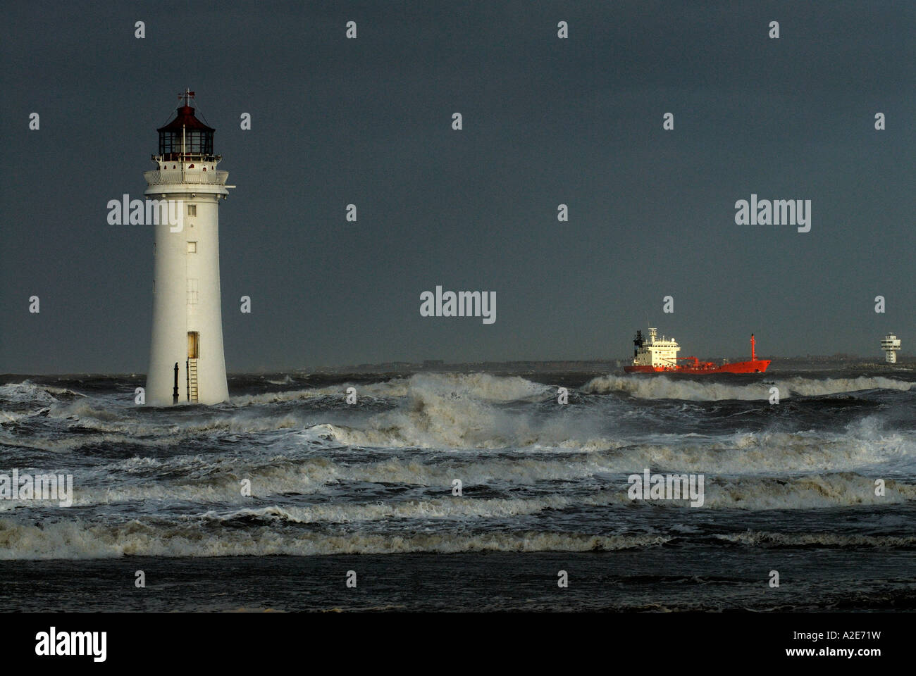 Perch Rock Lighthouse in stormy seas while a ship passes in the ...