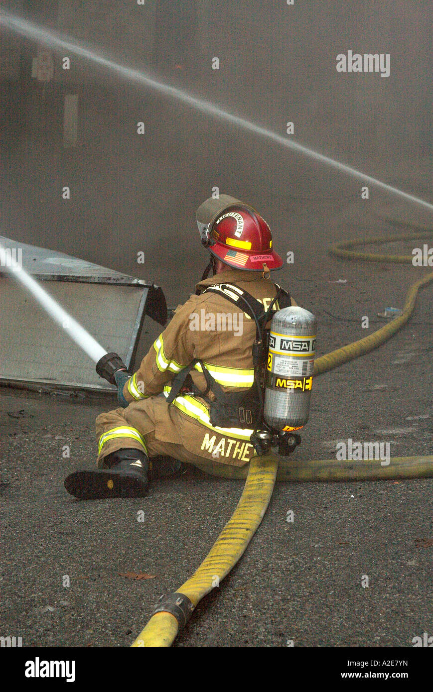 Fireman spraying water on a commercial warehouse fire filled with ...