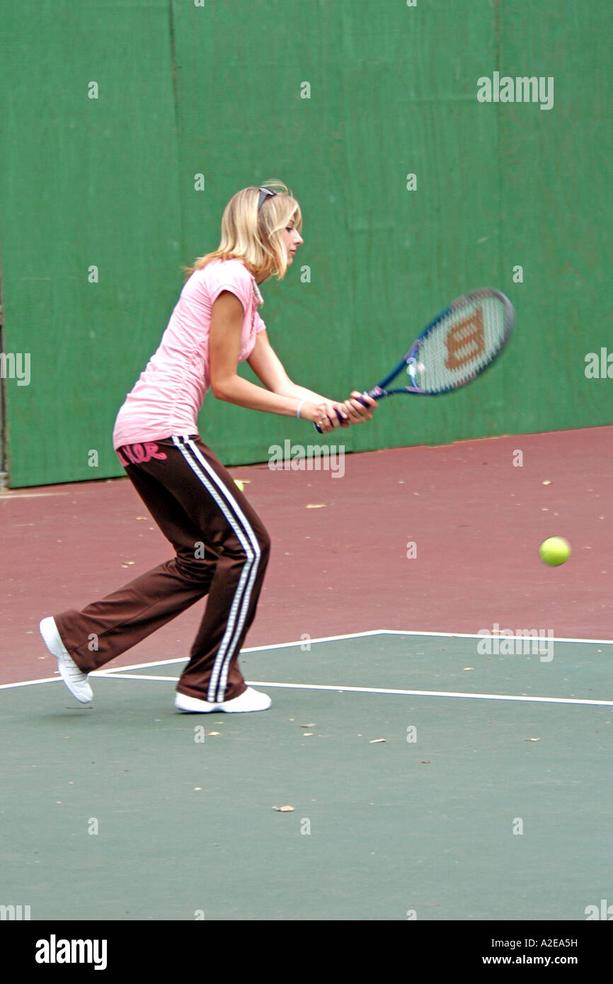Teenage female High school student learns to play Tennis in a public ...