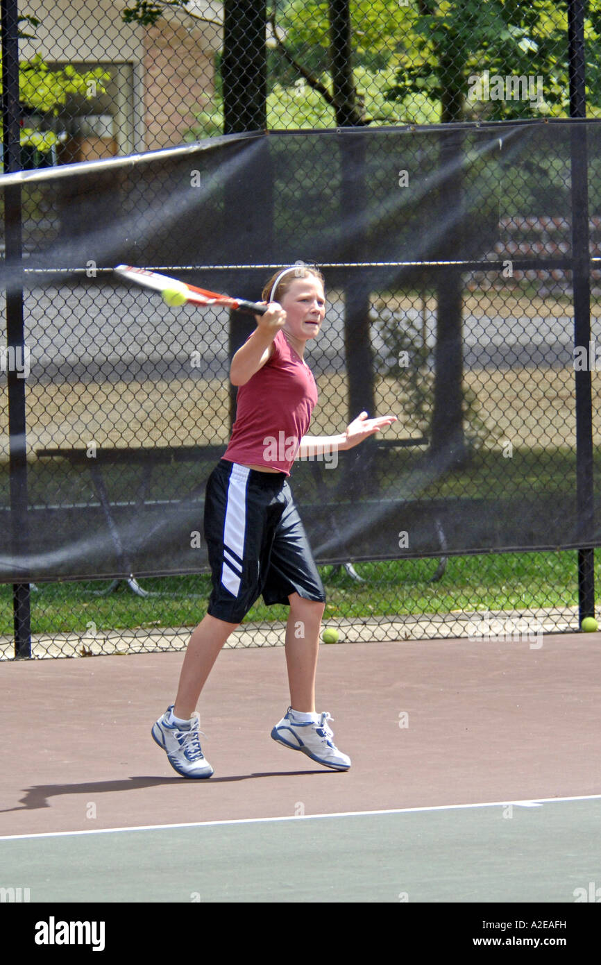 Teenage female High school student learns to play Tennis in a public ...