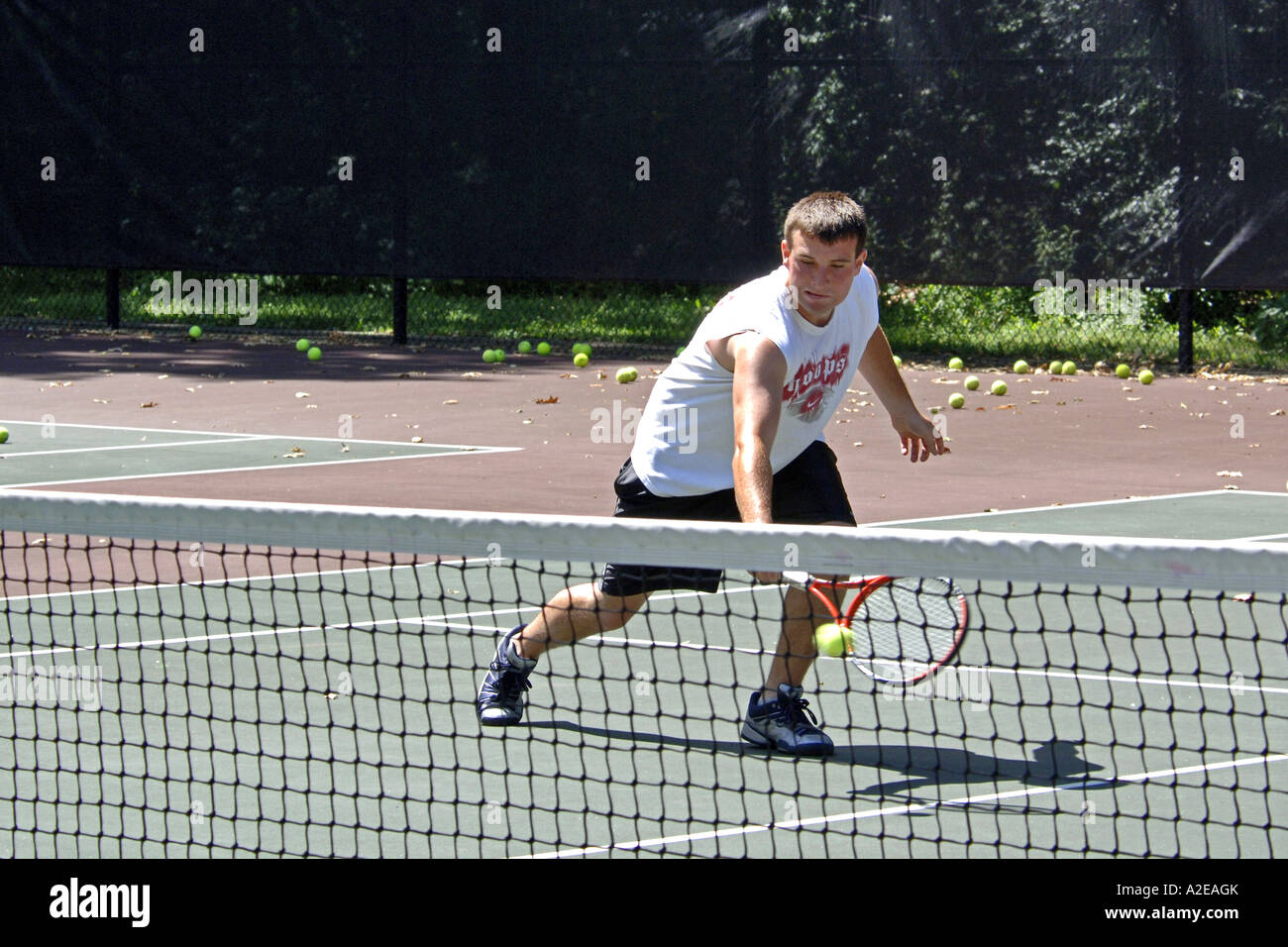 Teenage male High school student learns to play Tennis in a public ...