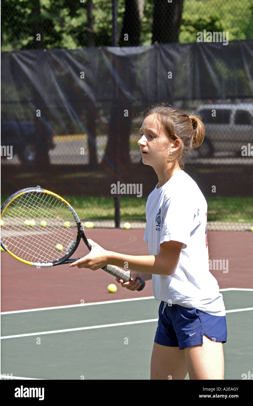 Teenage female High school student learns to play Tennis in a public ...
