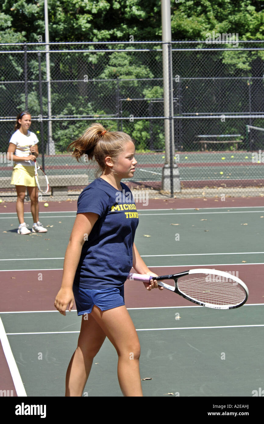 Teenage female High school student learns to play Tennis in a public ...