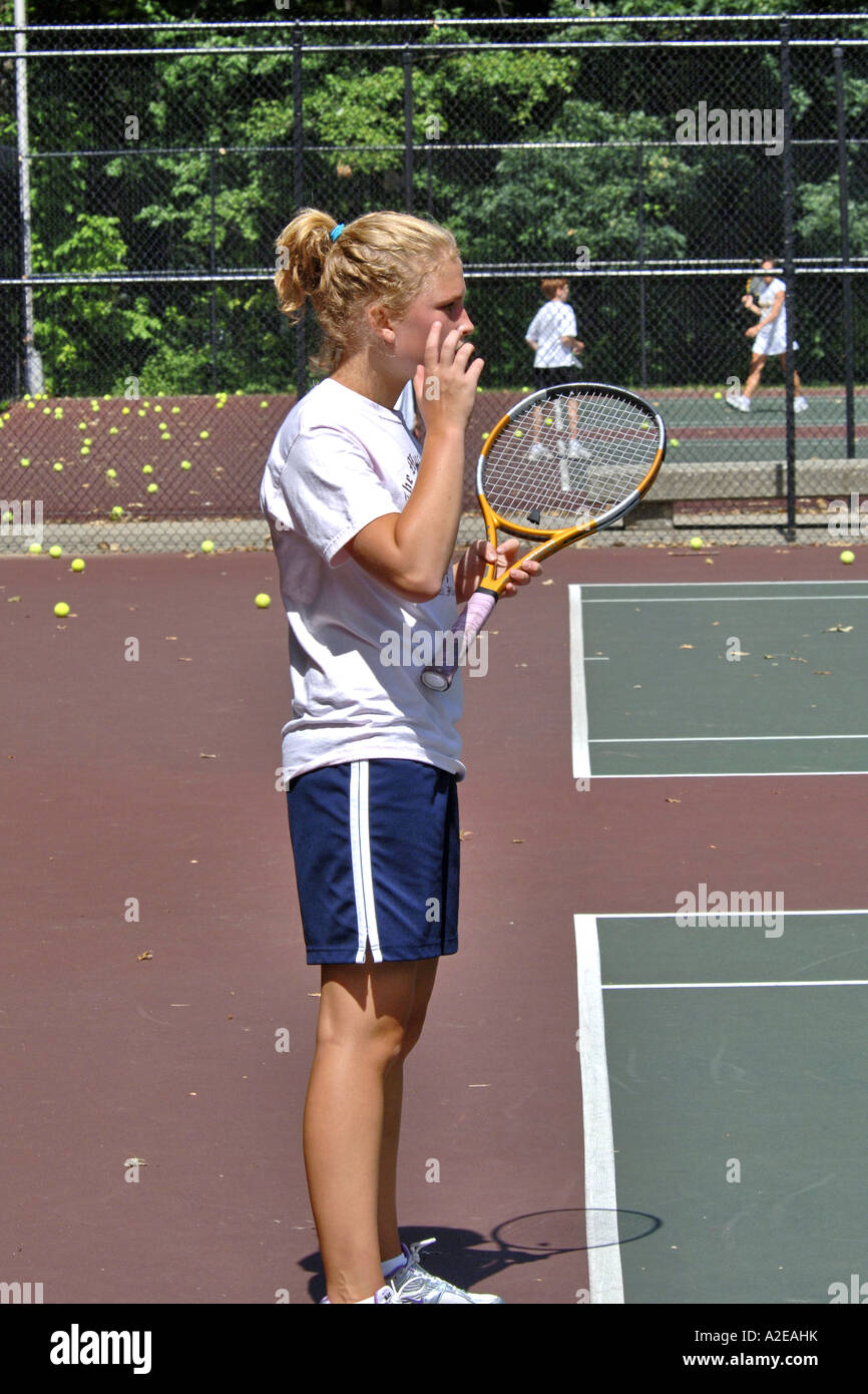 Teenage female High school student learns to play Tennis in a public ...