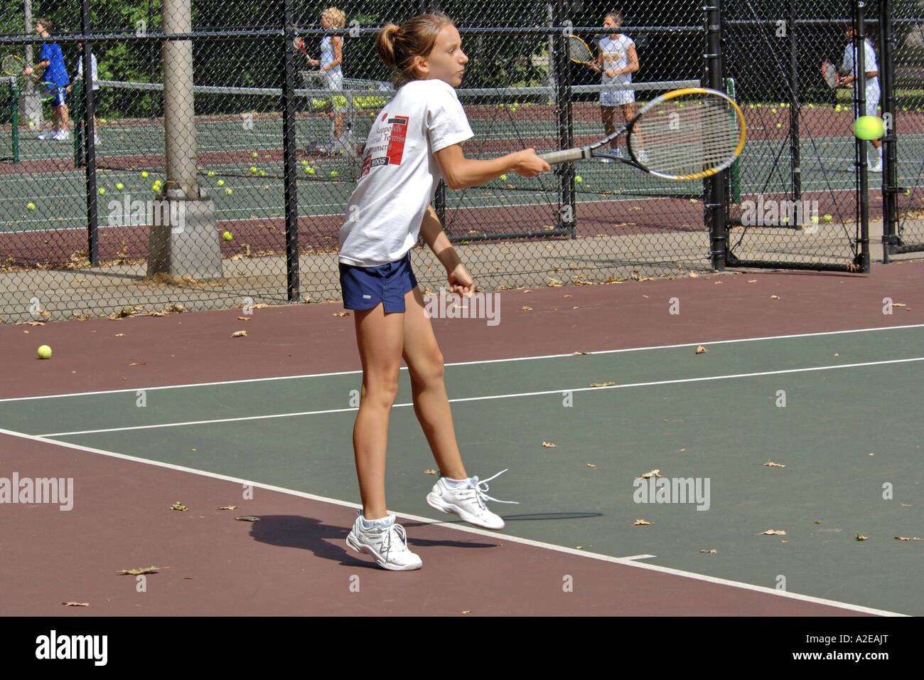 Teenage female High school student learns to play Tennis in a public ...