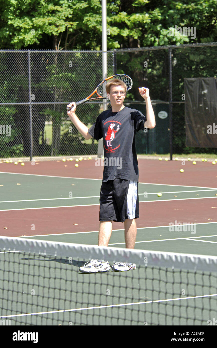Teenage male High school student learns to play Tennis in a public ...