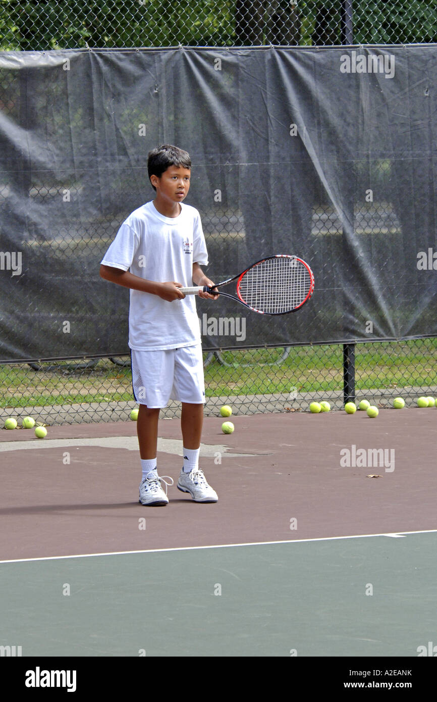 Teenage asian male taking Tennis lessons in a public summer-school ...