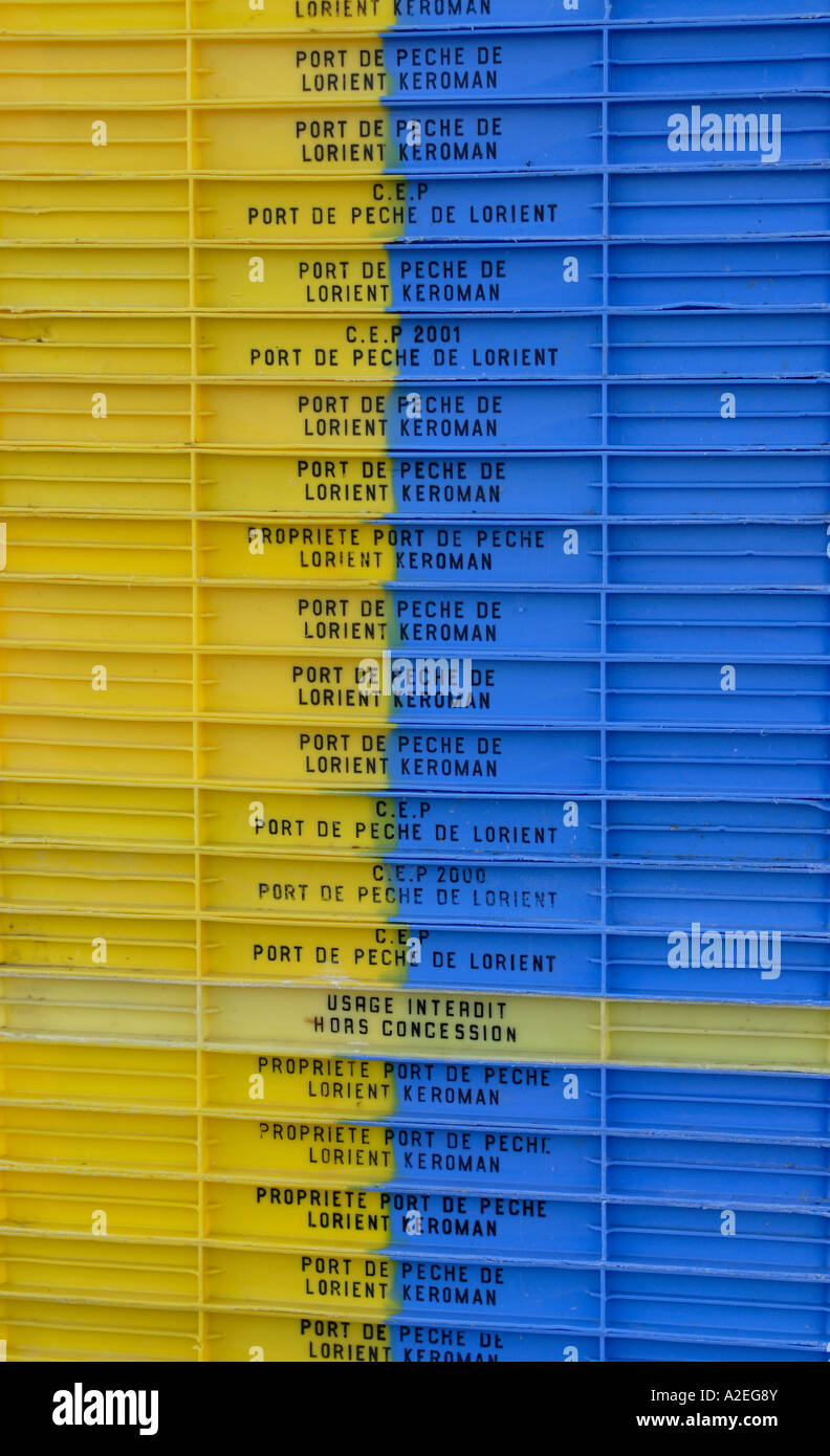 A stack of empty yellow and blue plastic fish boxes on the quay at ...