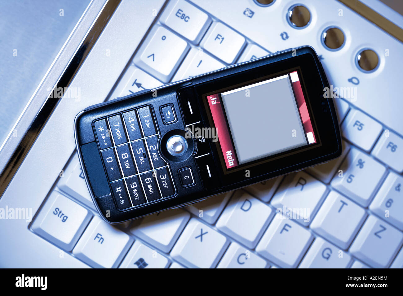 Mobile phone on keyboard, elevated view Stock Photo - Alamy