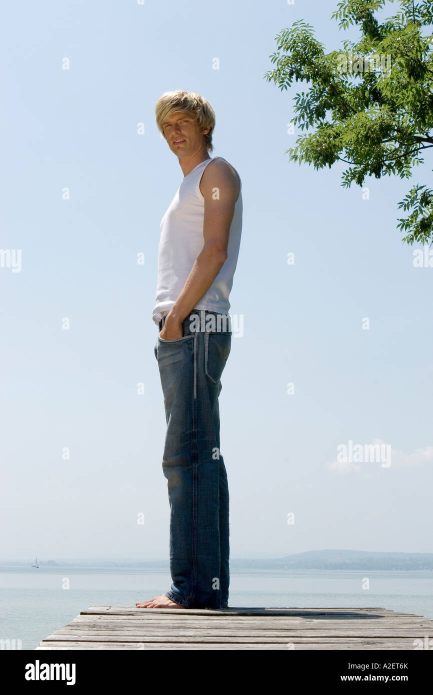 Young man standing on jetty, side view Stock Photo - Alamy