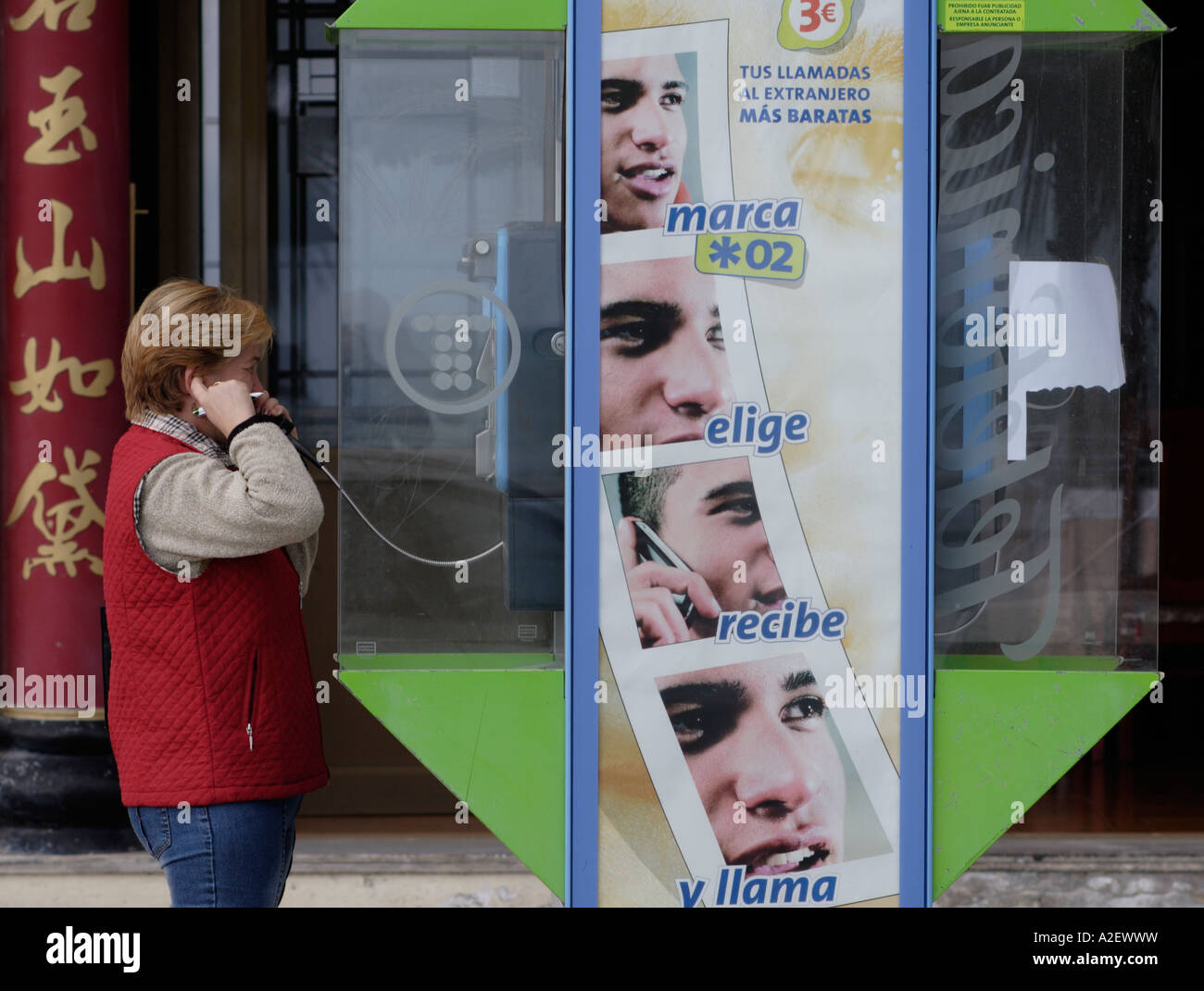 Spanish woman using a street payphone Stock Photo - Alamy