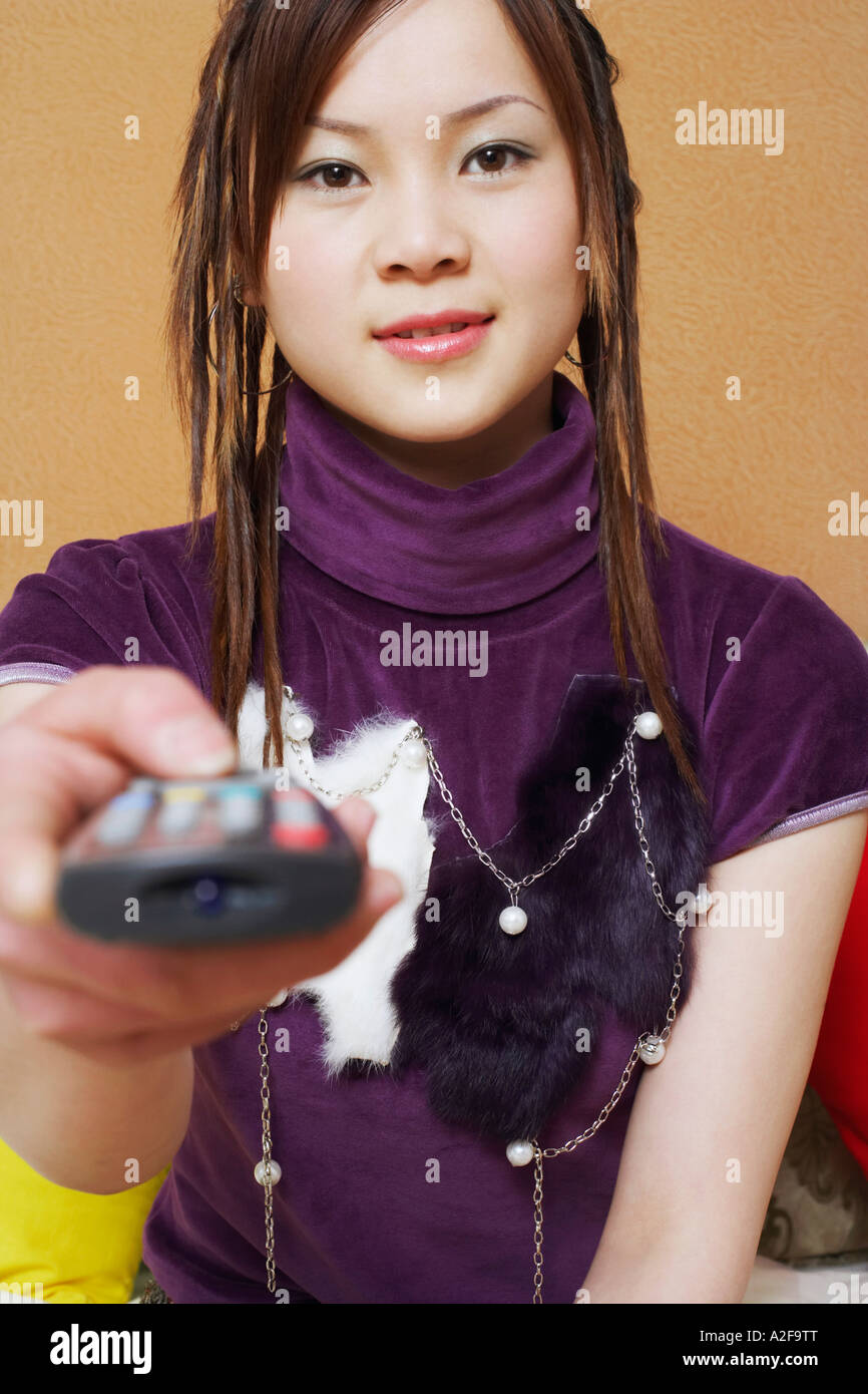 Portrait of a young woman holding a remote control Stock Photo - Alamy