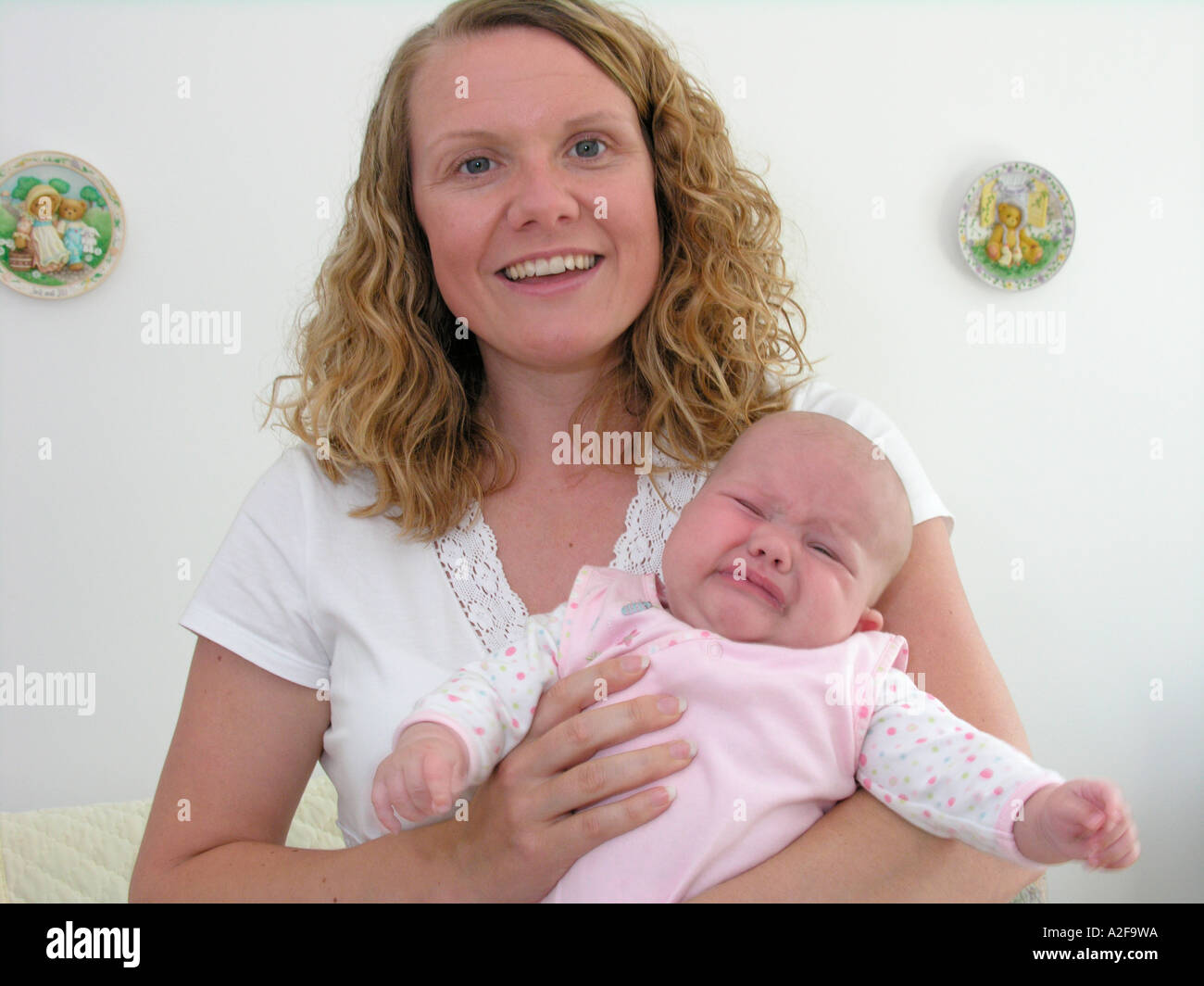 proud mother trying to calm down crying baby daughter Stock Photo - Alamy