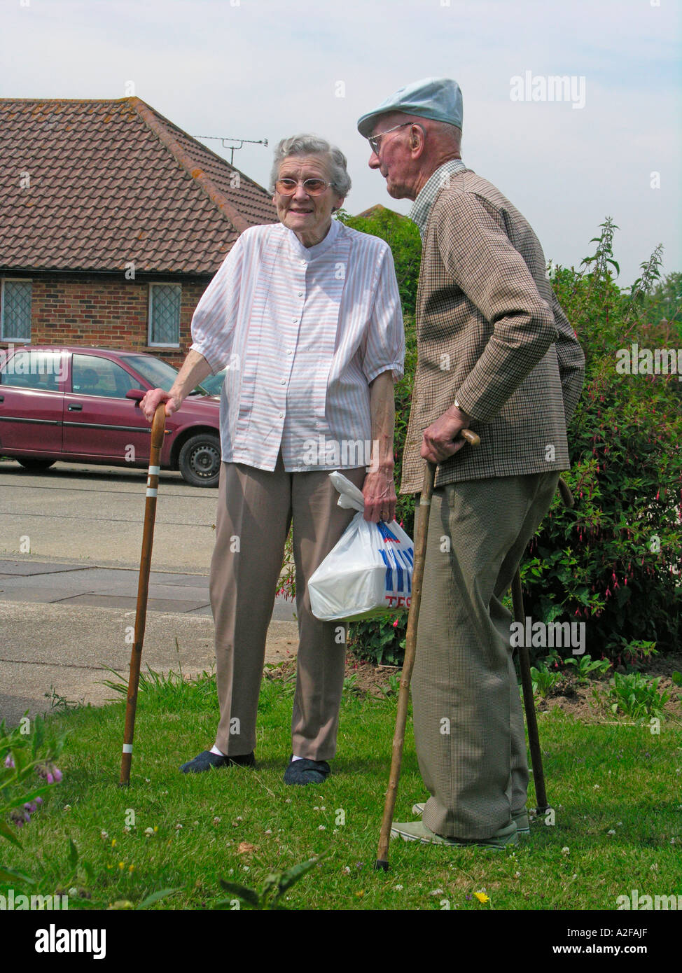 partially disabled elderly man and woman using walking sticks having a ...