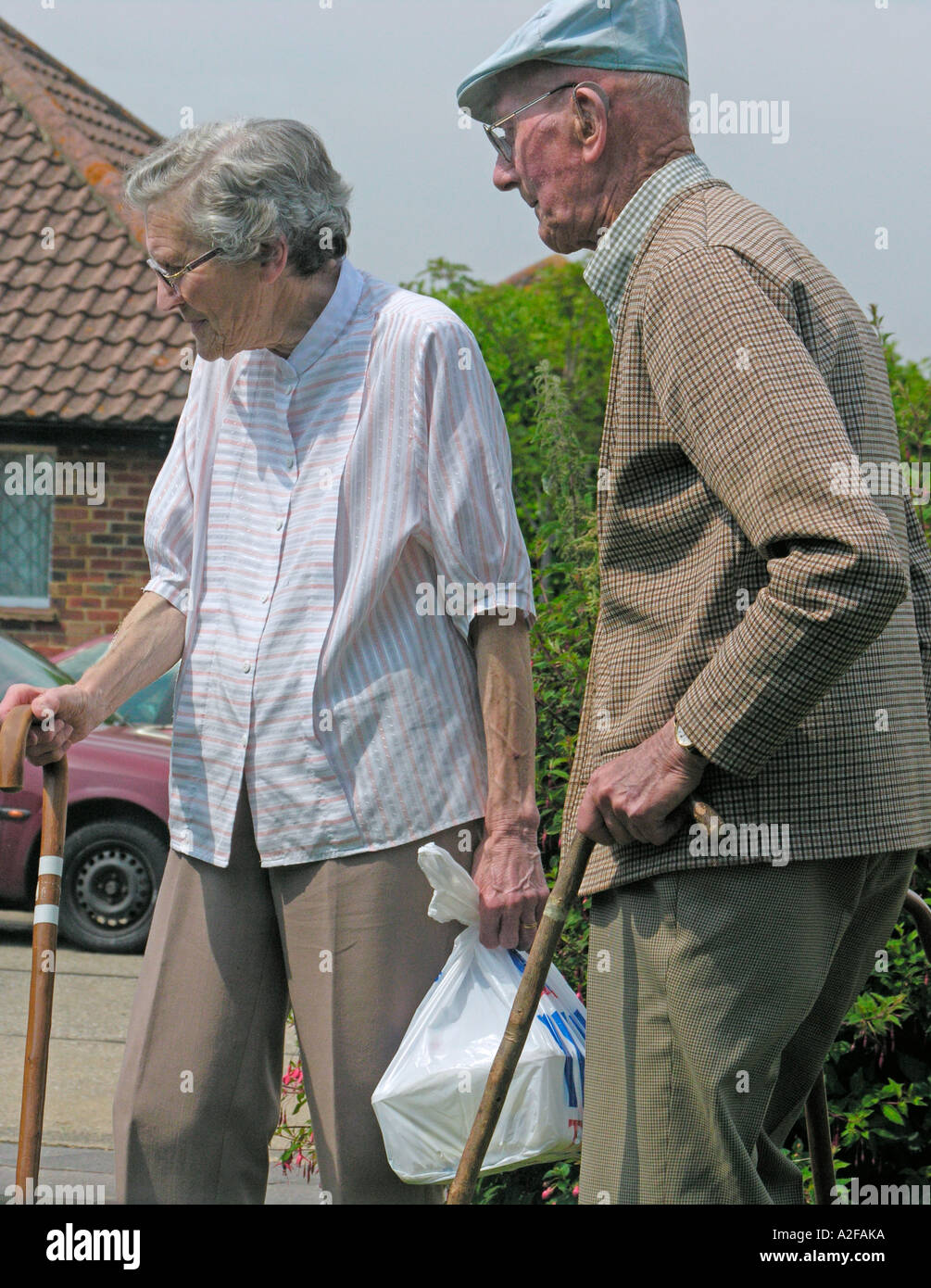 partially disabled elderly man and woman using walking sticks having a ...