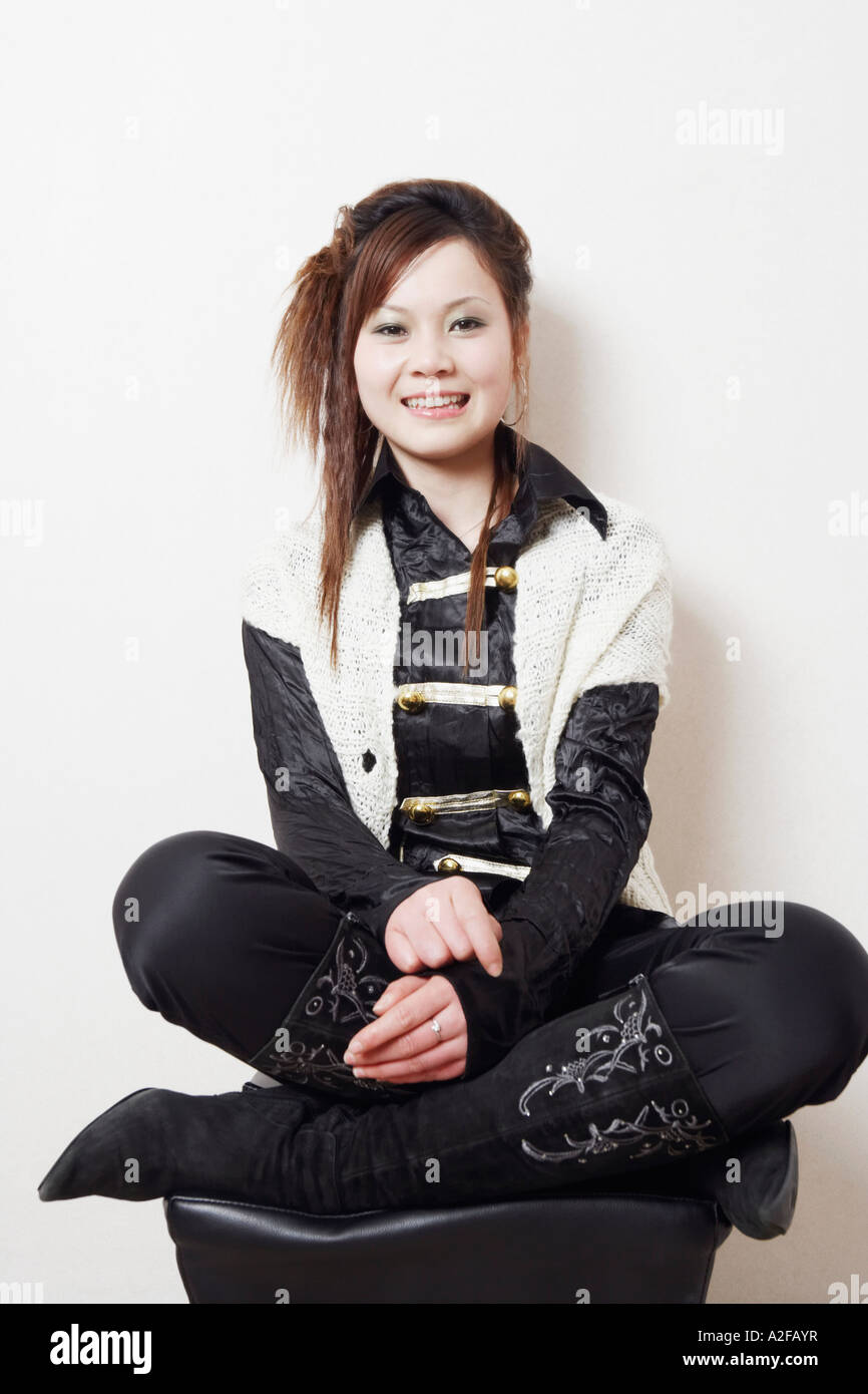 Portrait of a young woman sitting cross-legged Stock Photo - Alamy