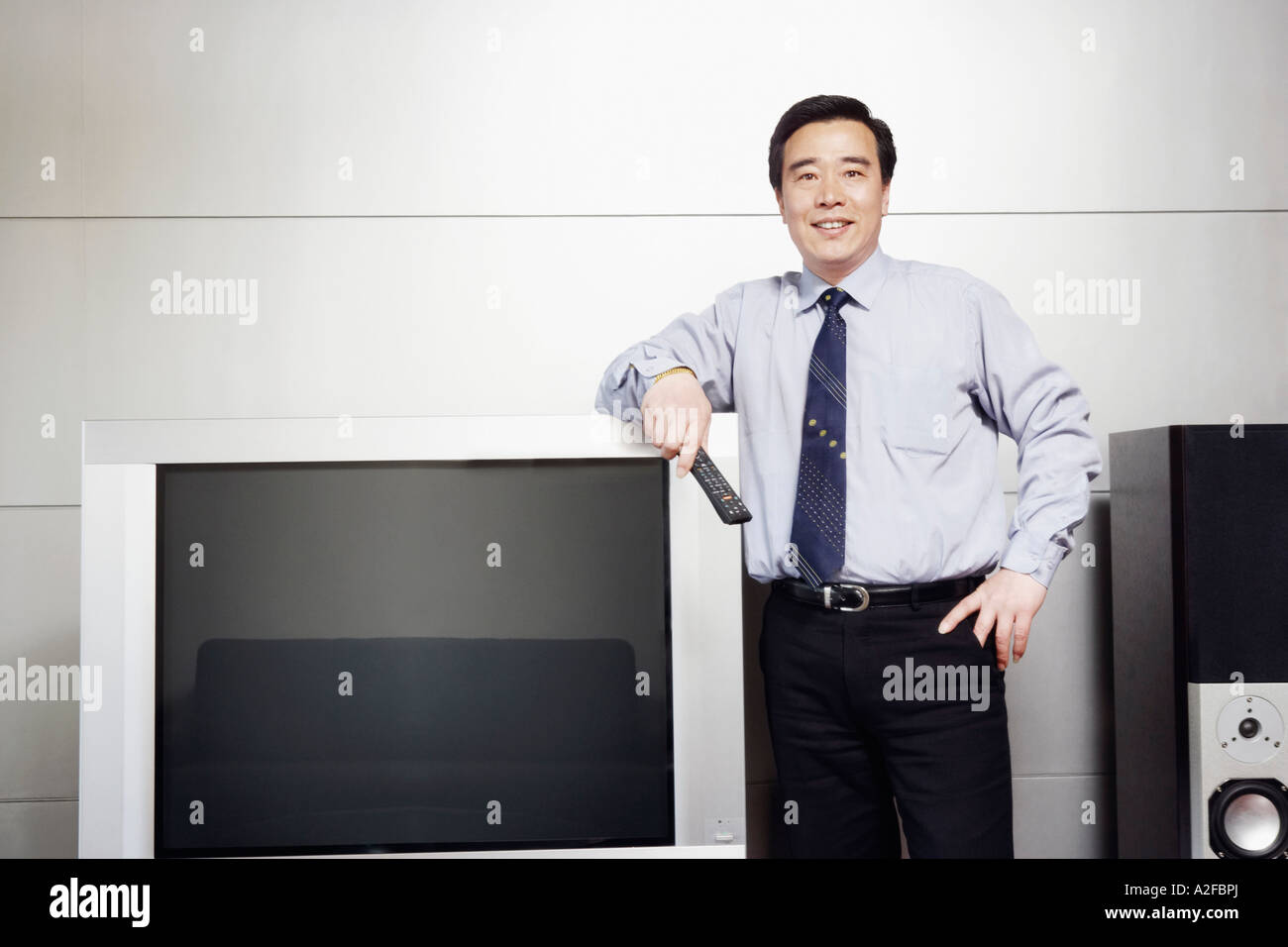 Businessman standing beside a television smiling Stock Photo - Alamy