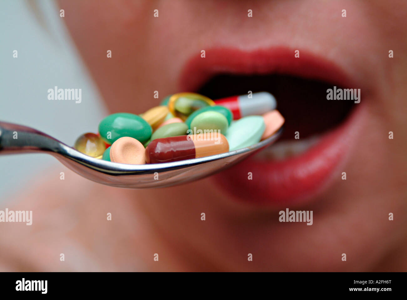 Spoon filled with many different colourful pills and capsules getting ...