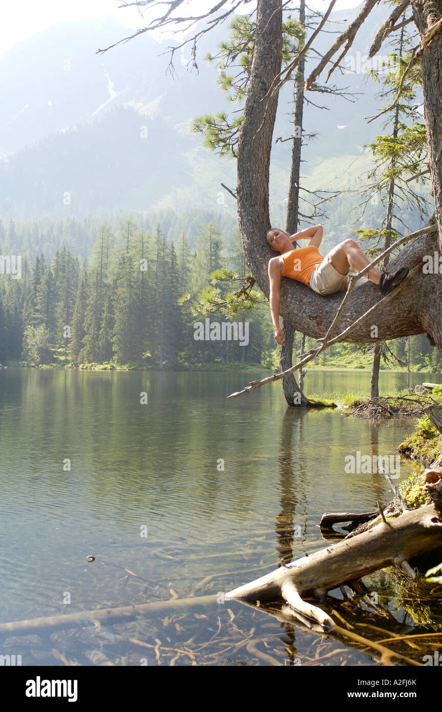 Young woman lying on branch of tree Stock Photo - Alamy