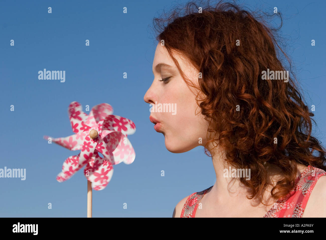 Young woman blowing pin wheel, side view Stock Photo - Alamy