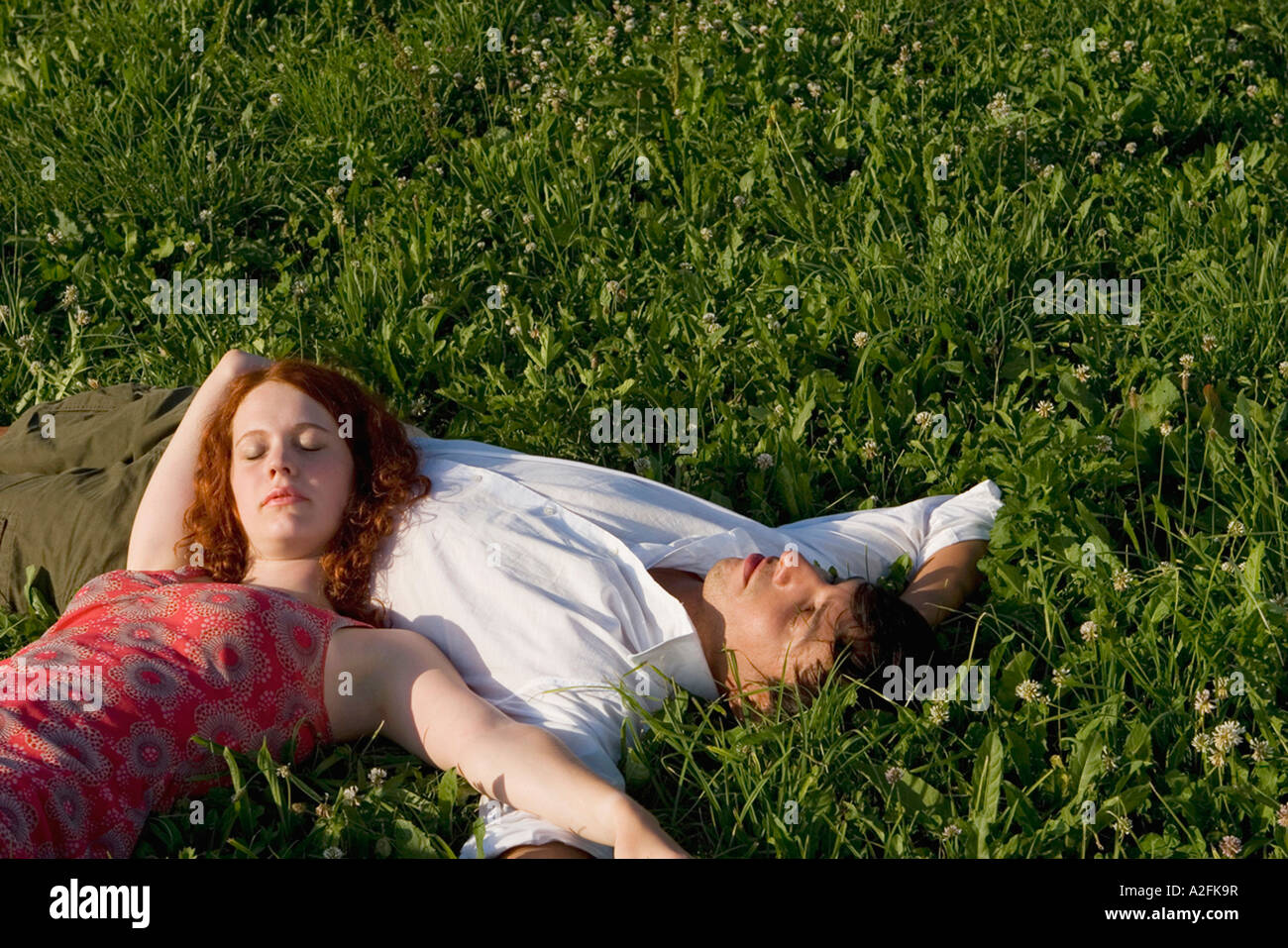 Woman lying with head on man`s belly in meadow Stock Photo - Alamy