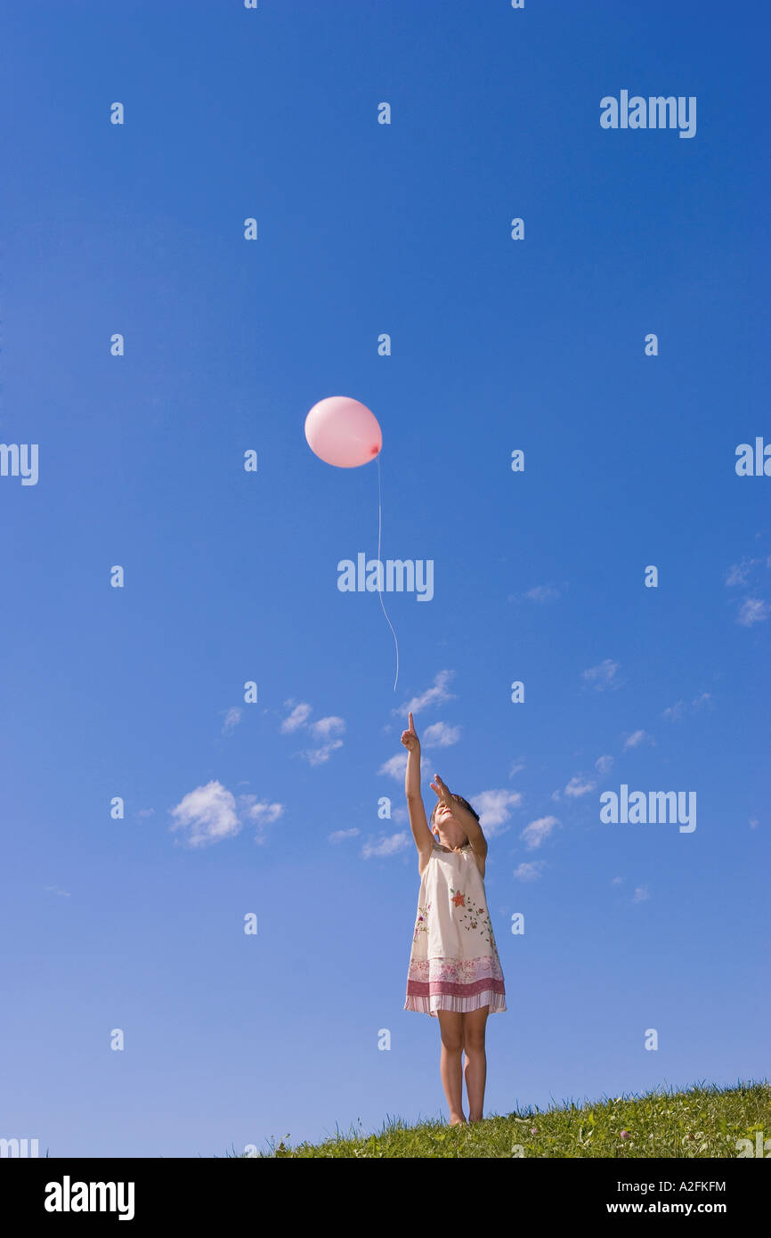 Girl (7-9) standing in meadow, pointing at balloon Stock Photo - Alamy