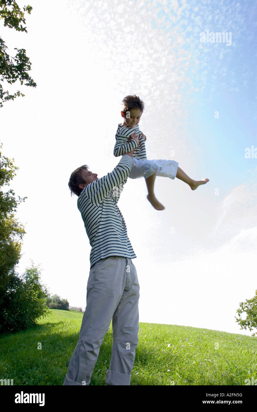 Father lifting son (4-7) in park, side view Stock Photo - Alamy