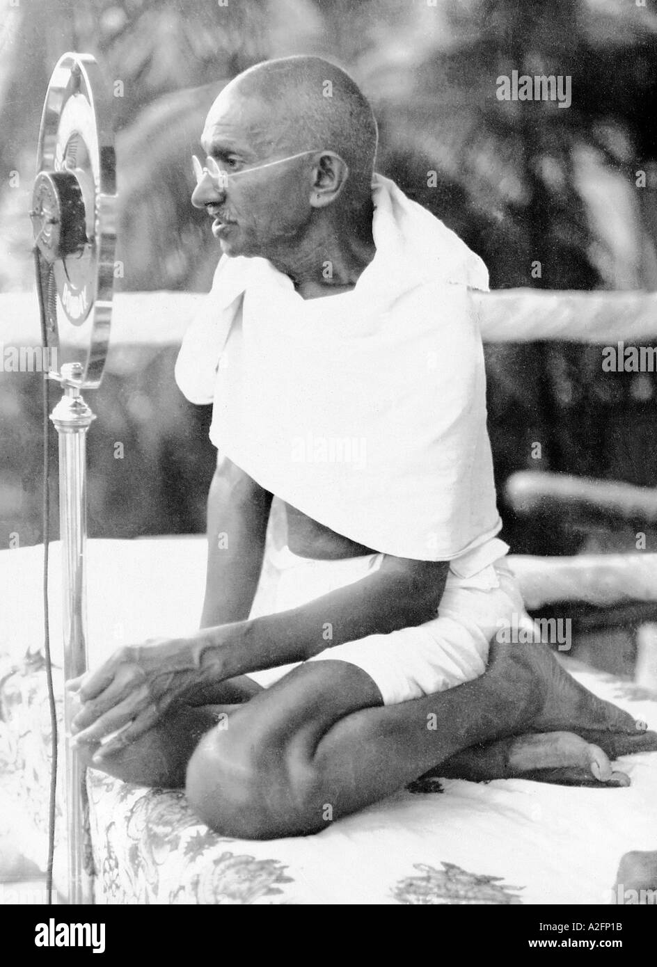 Mahatma Gandhi sitting and addressing on microphone a public meeting at ...