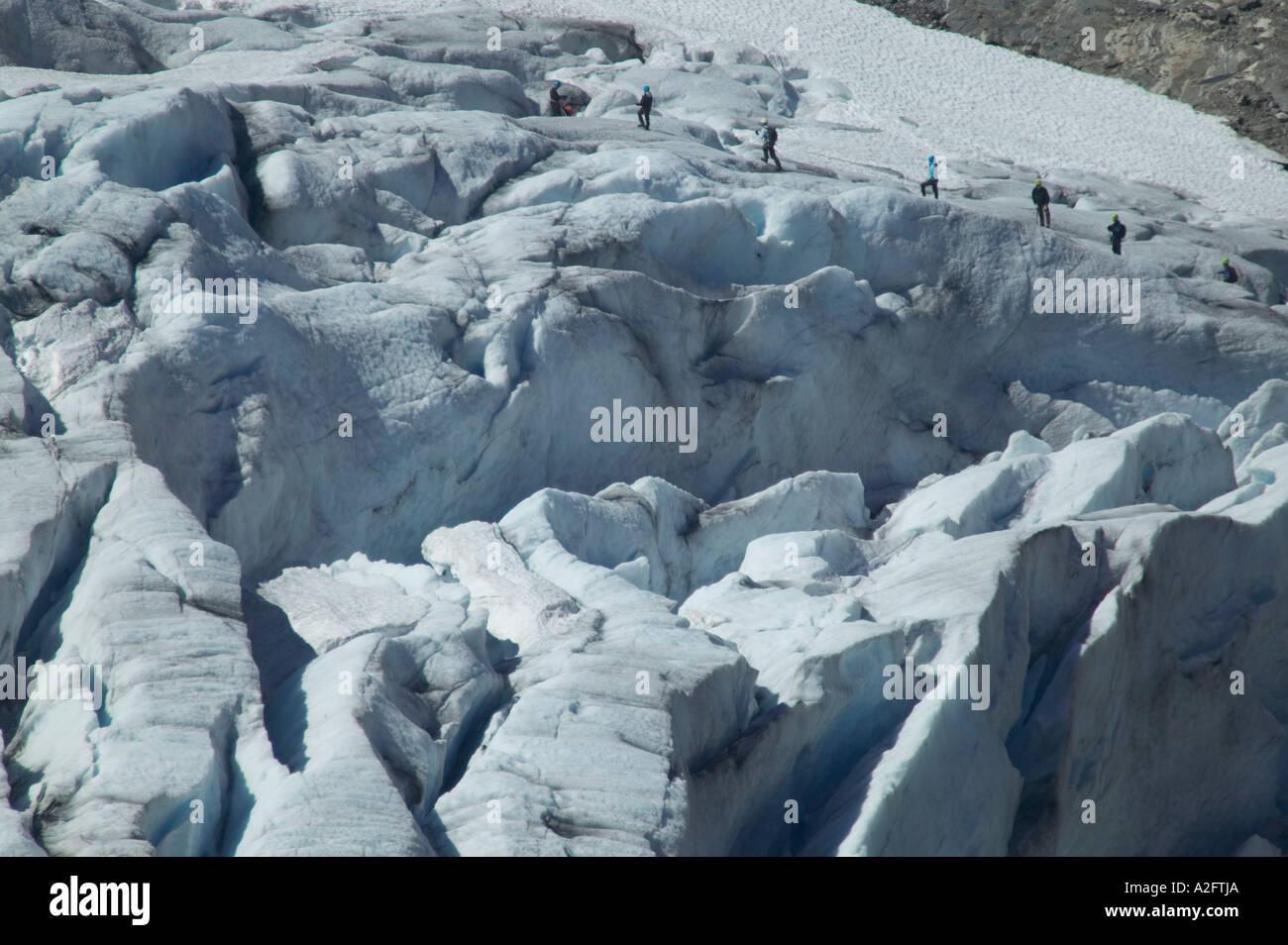 Glacier hikers wind through the blue ice crevices and over snow fields ...