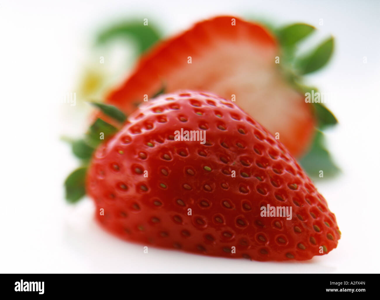 Close up of a strawberry with a cut half behind on a white background ...