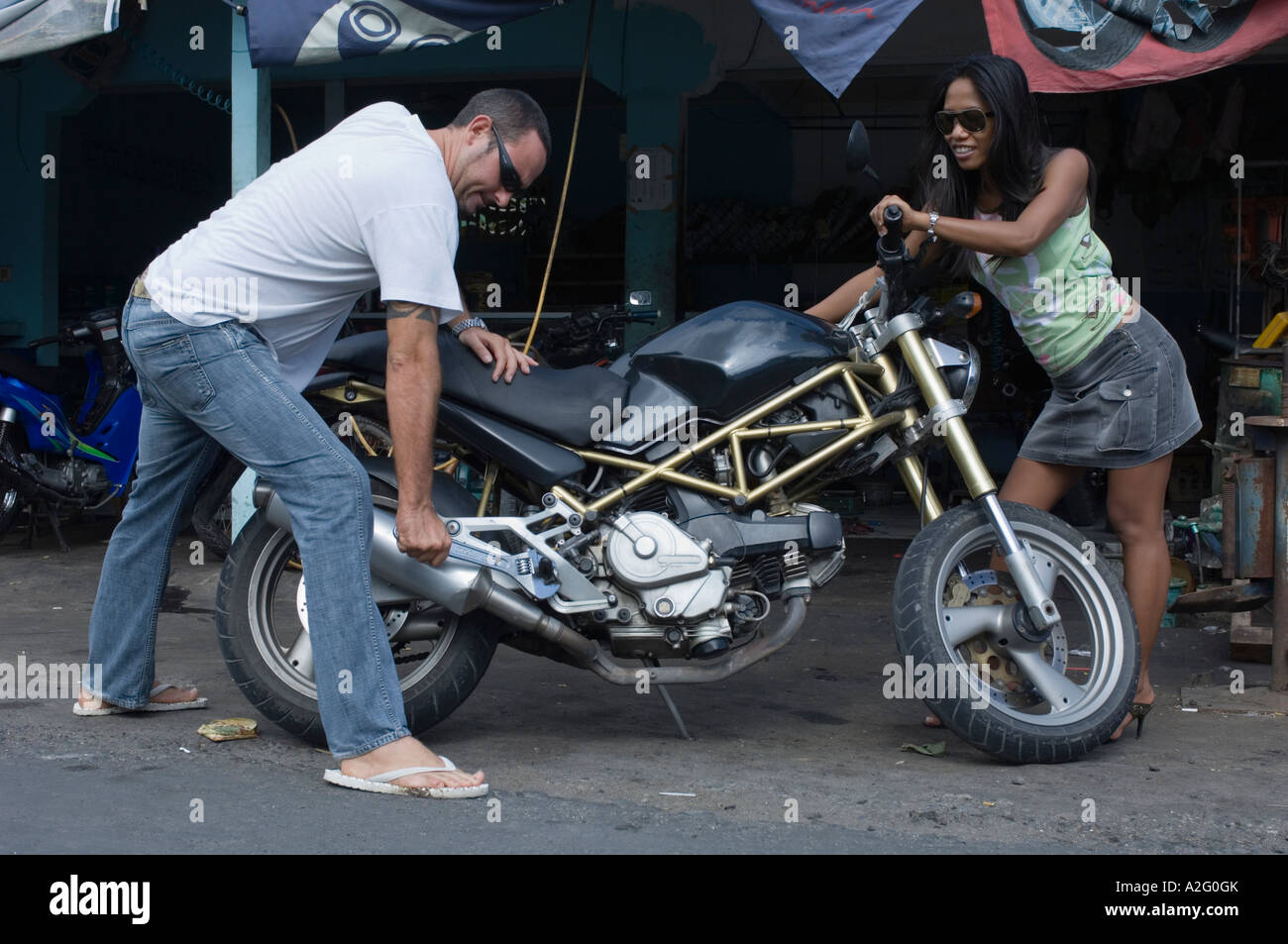 couple fixing motorcycle at workshop Stock Photo - Alamy