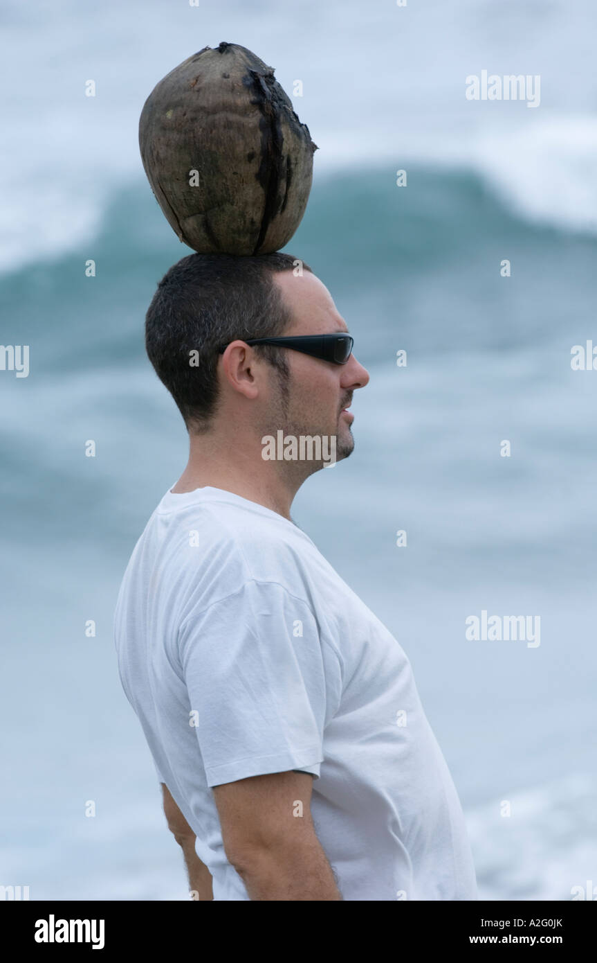 man with coconut on his head with sea in the background Stock Photo - Alamy