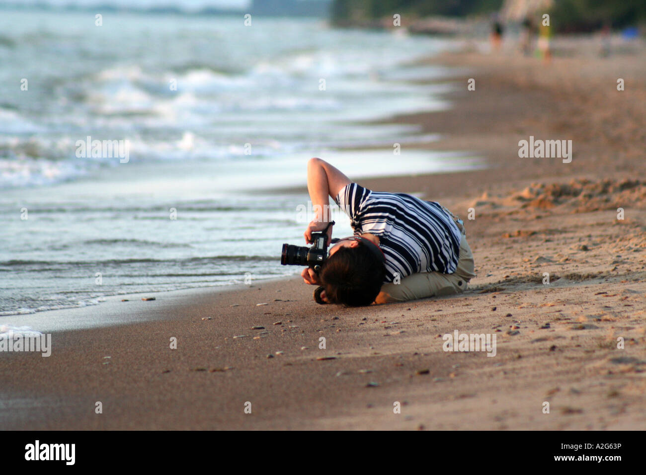 Photographer Lying on Sandy Beach Capturing Ocean Waves With Camera ...
