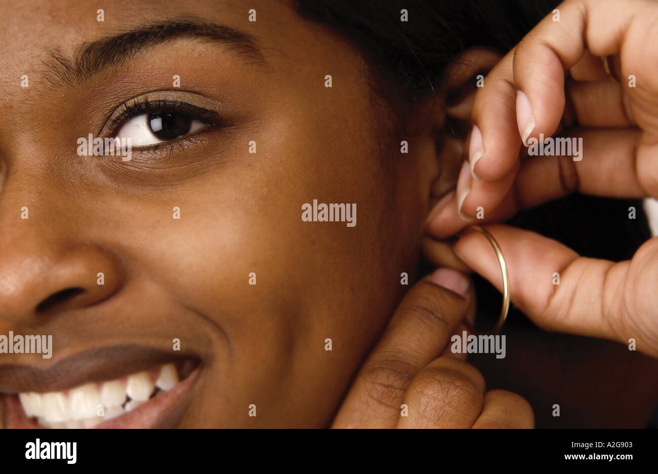 Woman putting on earring Stock Photo - Alamy