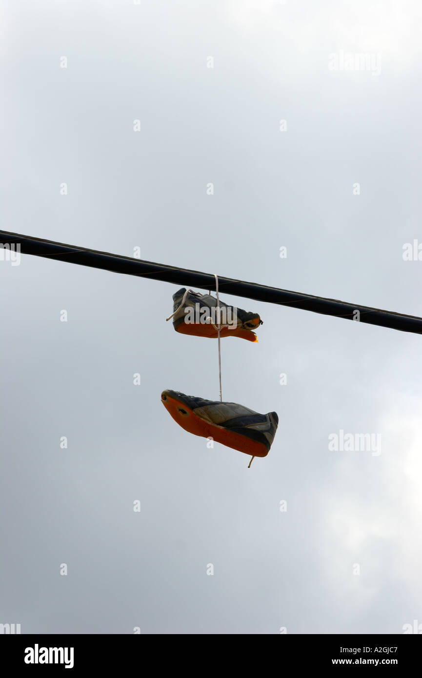 Old sneakers tied and hung from a power line Stock Photo - Alamy