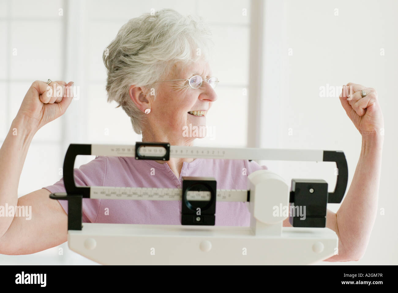 Senior woman weighing self on scale and cheering Stock Photo - Alamy