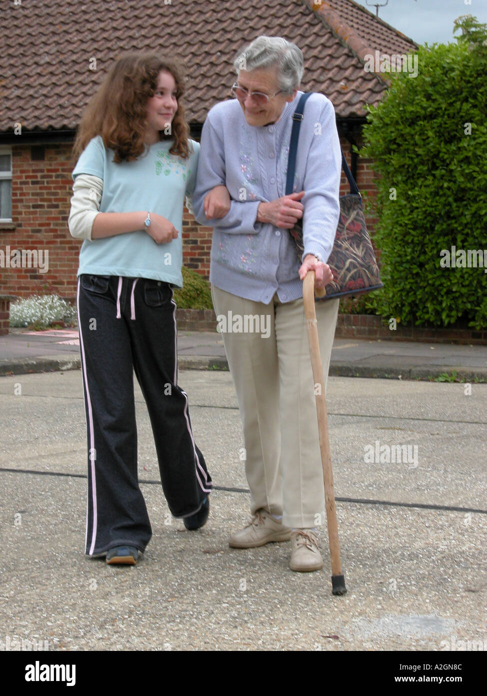 Young girl helping elderly woman across road Stock Photo - Alamy