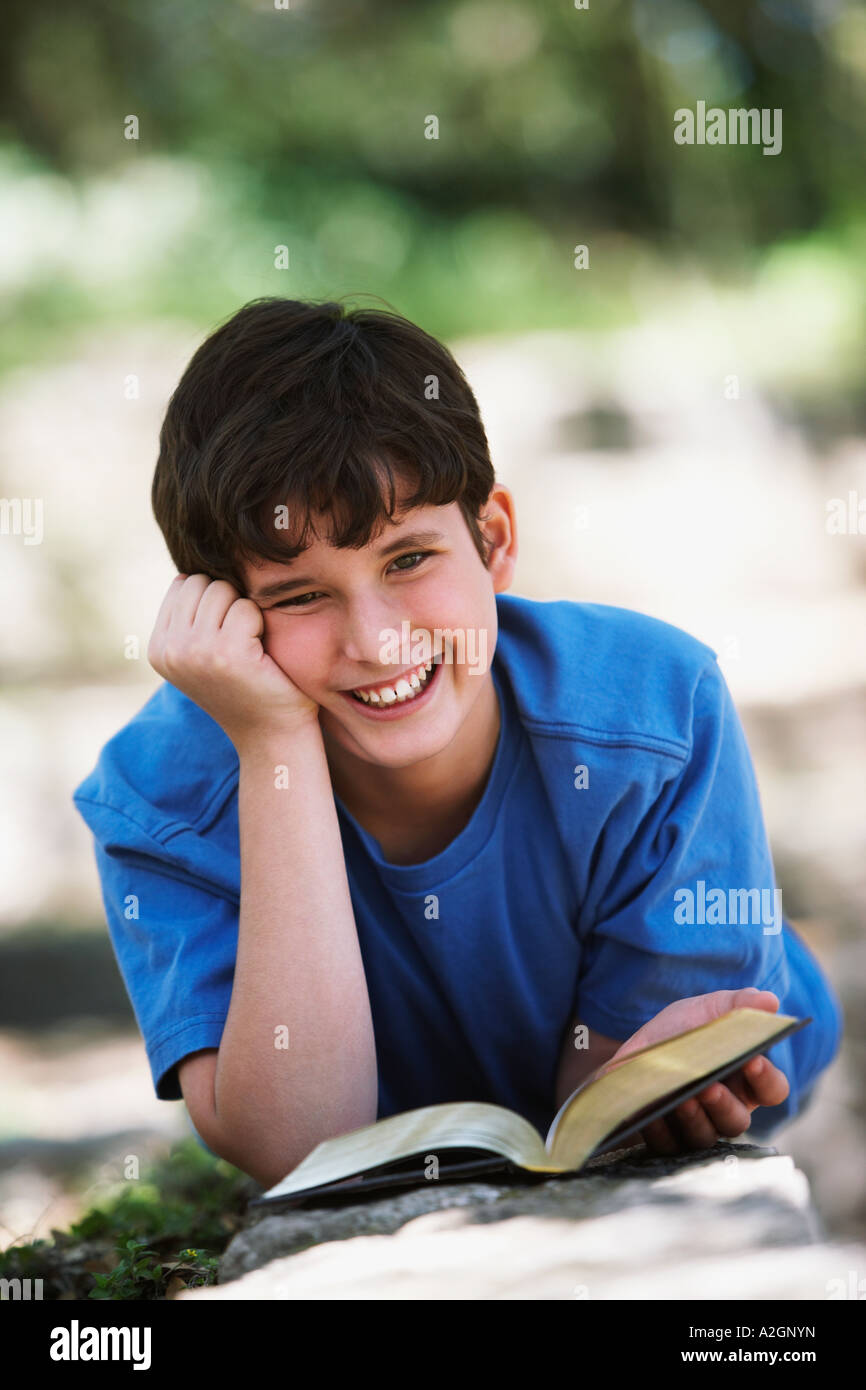 Boy smiling with book outdoors Stock Photo - Alamy