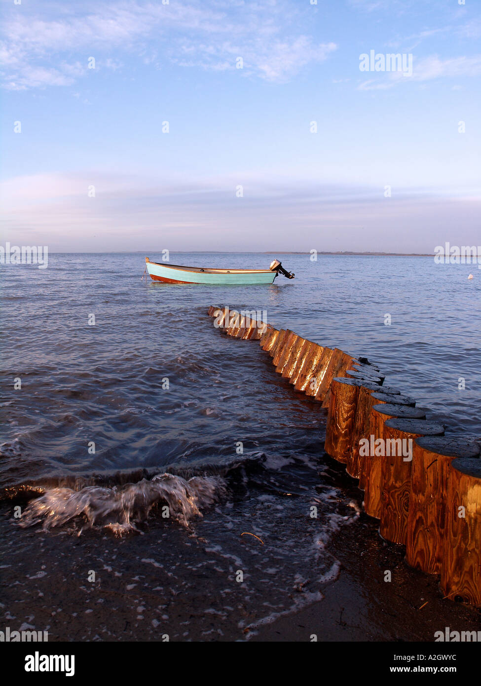 Spalshing water at groyne with dinghy in background Stock Photo - Alamy