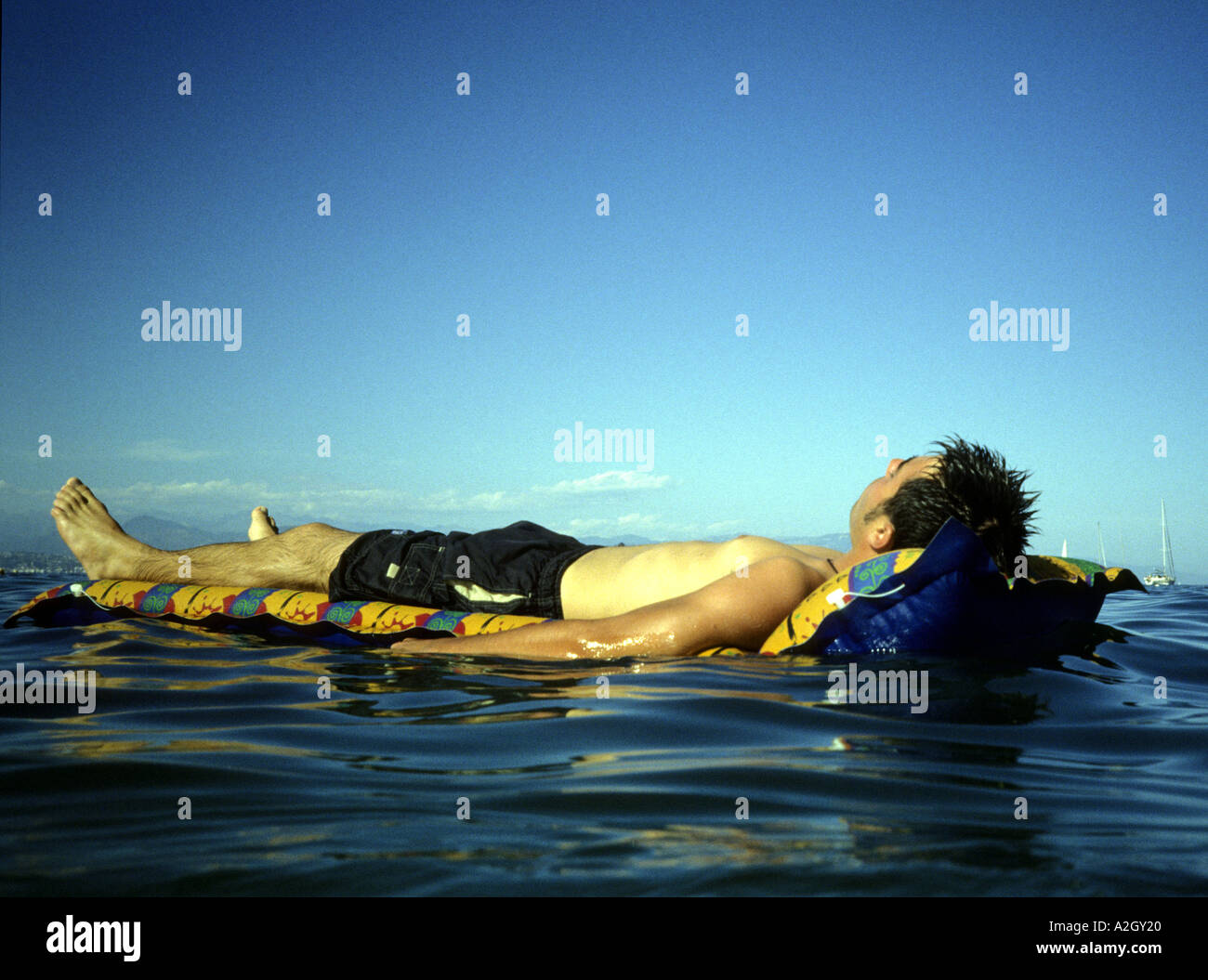 person asleep on airbed afloat off the beach Stock Photo - Alamy