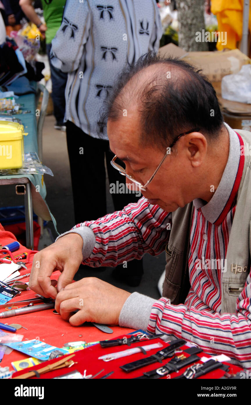 Asian watch maker making watch strap repair, Sunday street market ...