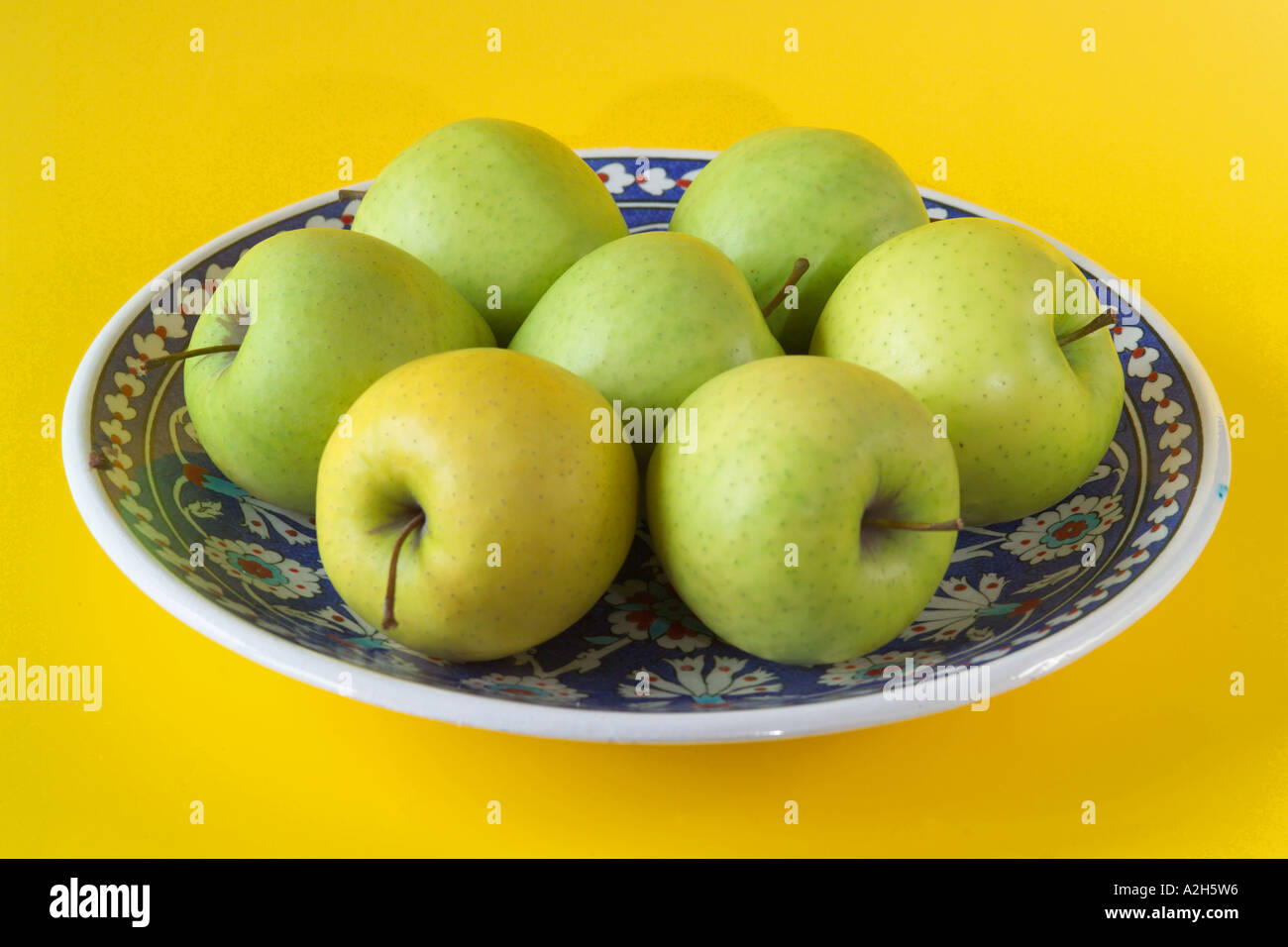 Seven green and yellow apples on the plate Stock Photo - Alamy