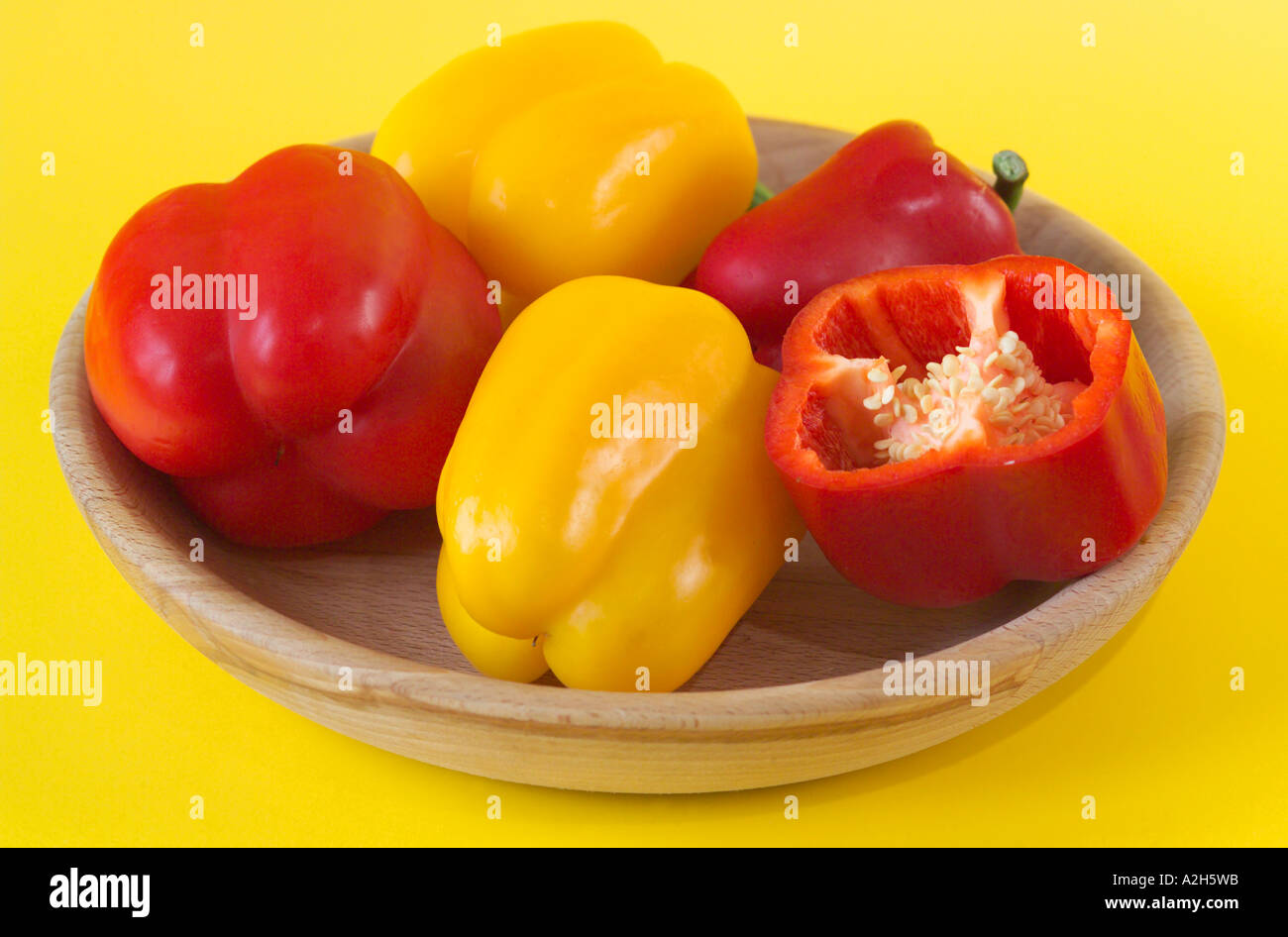 Red and yellow paprikas in the wooden bowl Stock Photo - Alamy