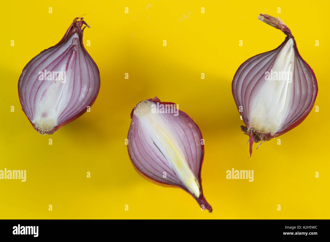 Three red onion halves on the yellow background Stock Photo - Alamy
