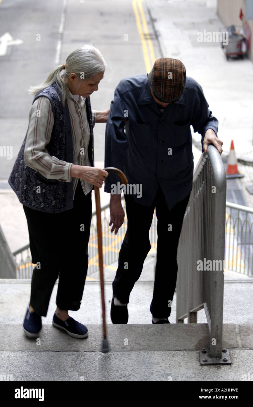 Woman helps her husband, a stroke victim, up the steps toward their ...