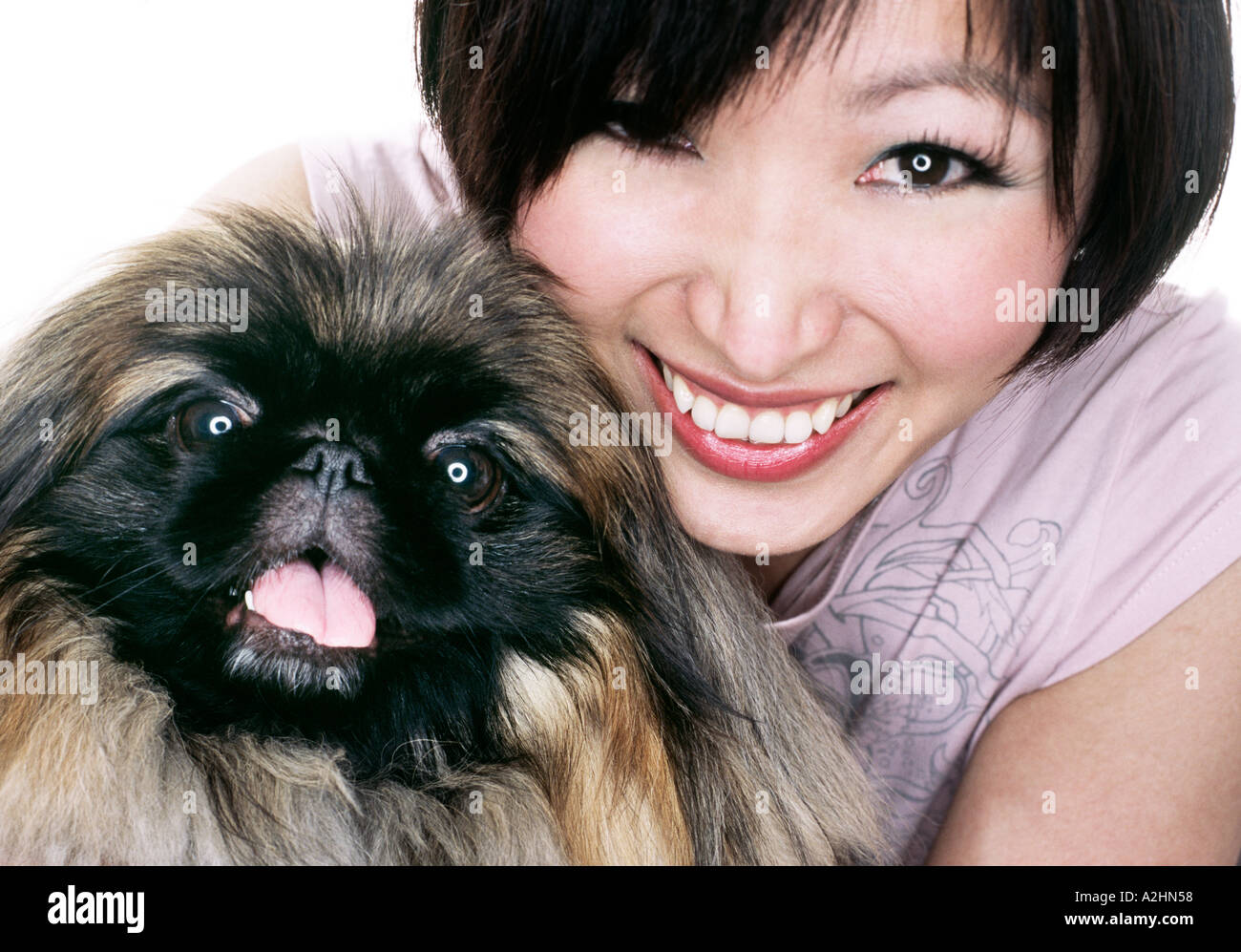 One young Asian female holding up a Pekinese breed dog in the air next ...