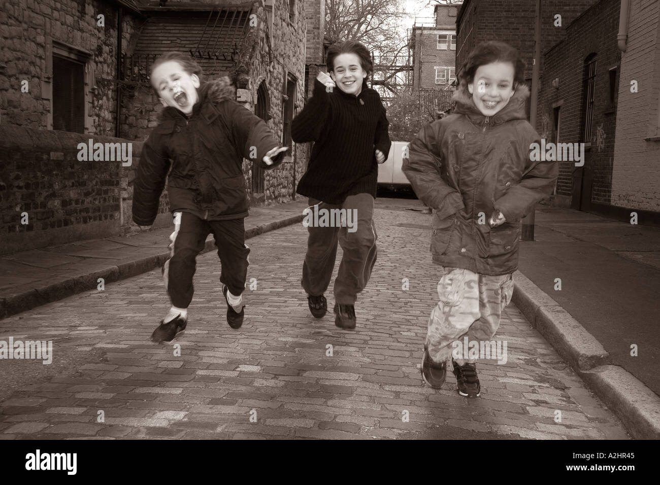 Three happy boys running up a cobbled street model released black and ...